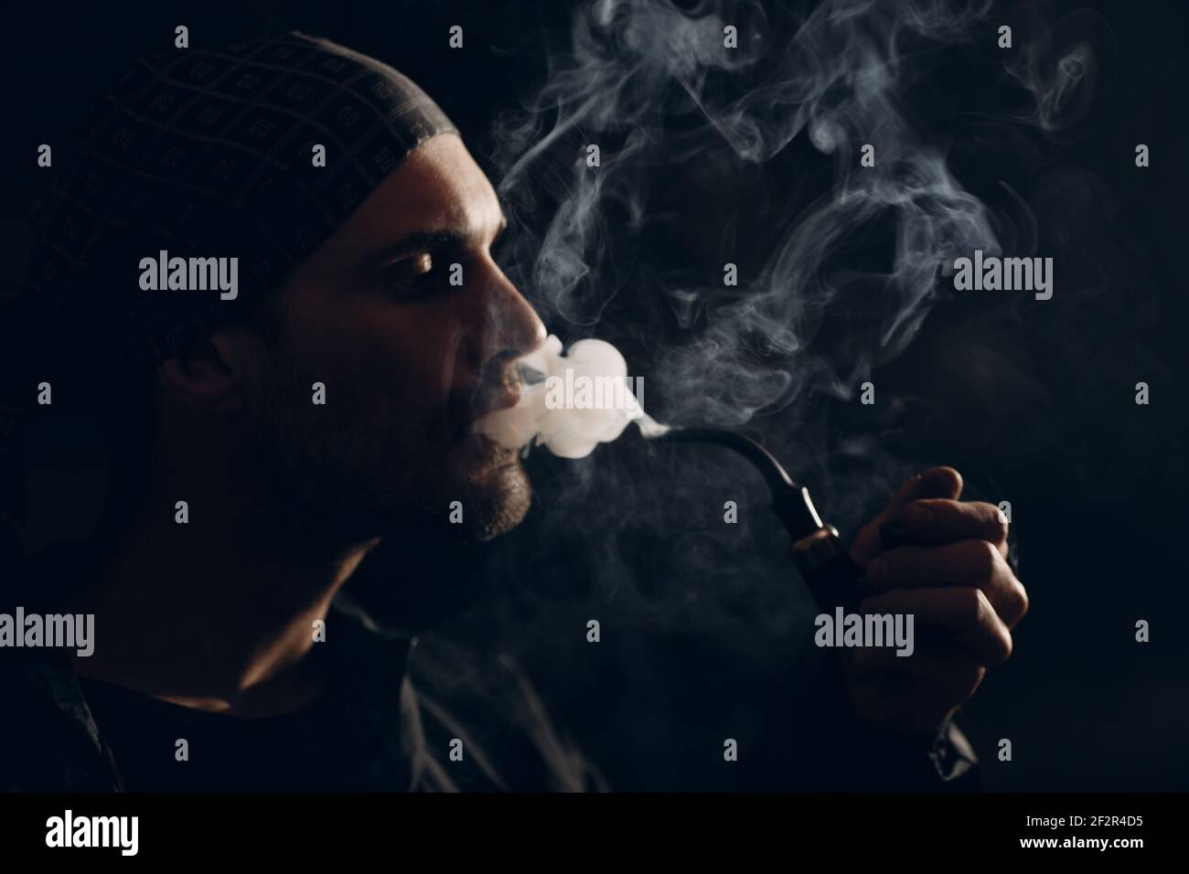 Man smoking a pipe on dark background. Back lit profile portrait Stock ...