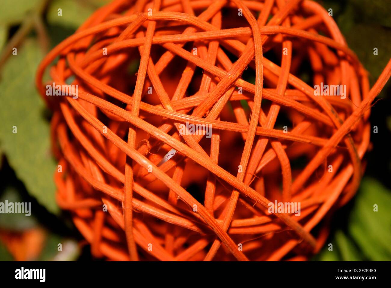 A closeup shot of an orange rubber thread tangled with blurred green ...