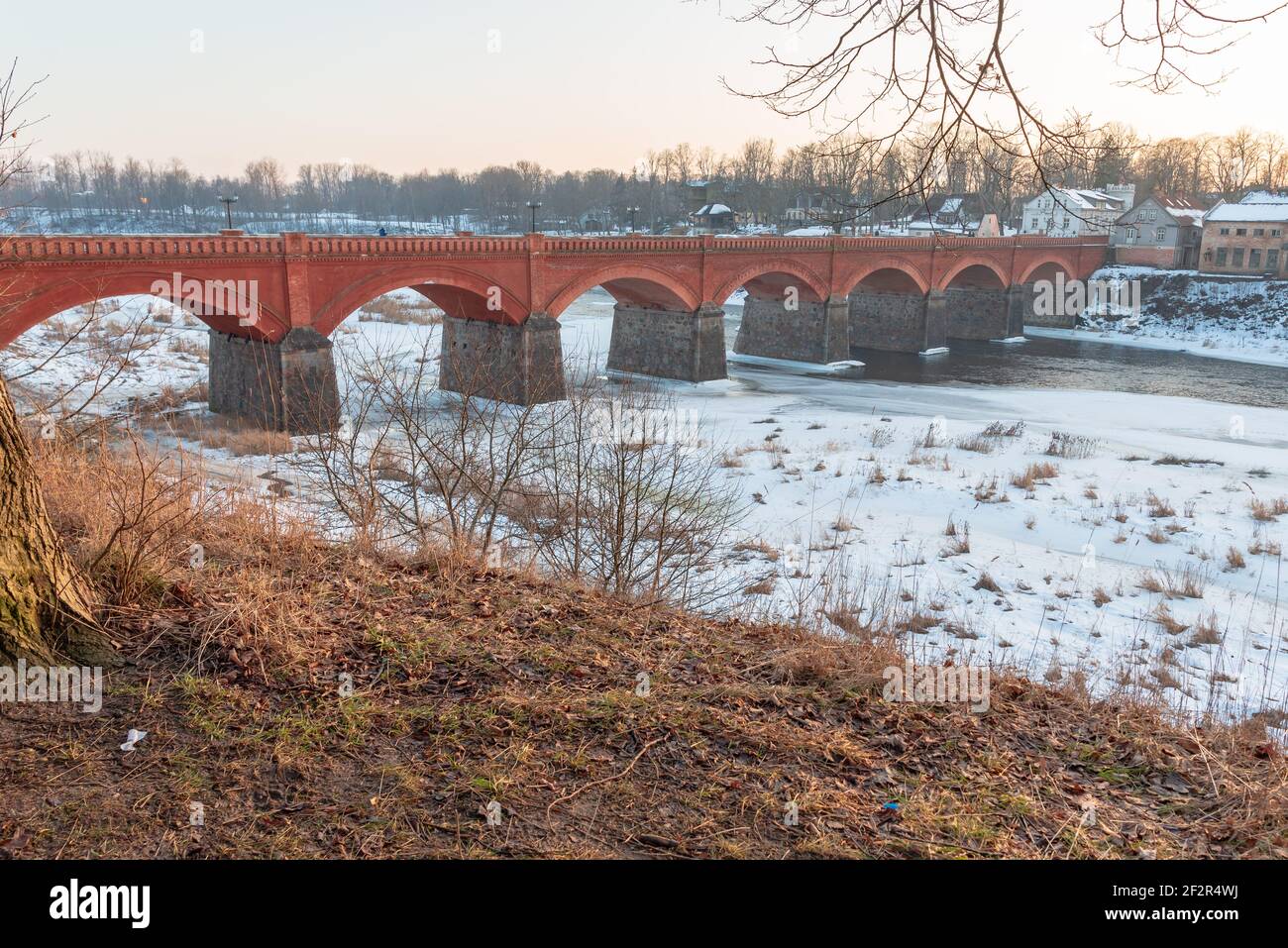 an ancient stone and red brick bridge over the river which in places is ...