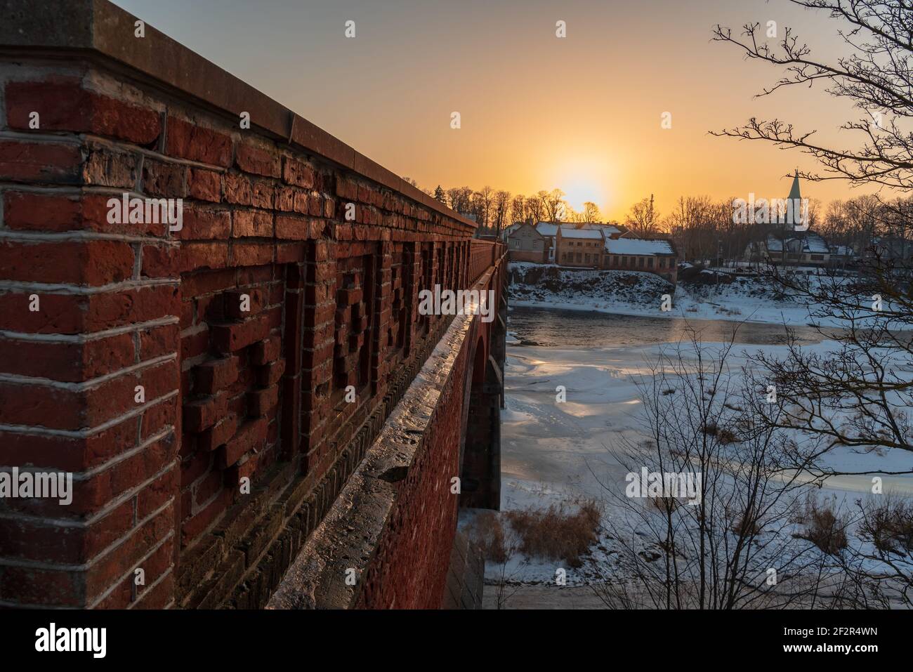an ancient stone and red brick bridge over the river in sunset light ...