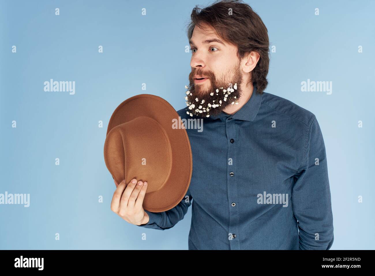Cheerful man hat in hand beard with flowers emotions blue background ...