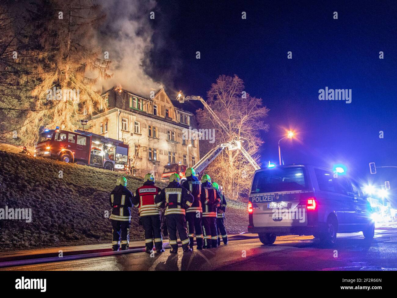 13 March 2021, Saxony, Schwarzenberg: Firefighters and police stand on ...