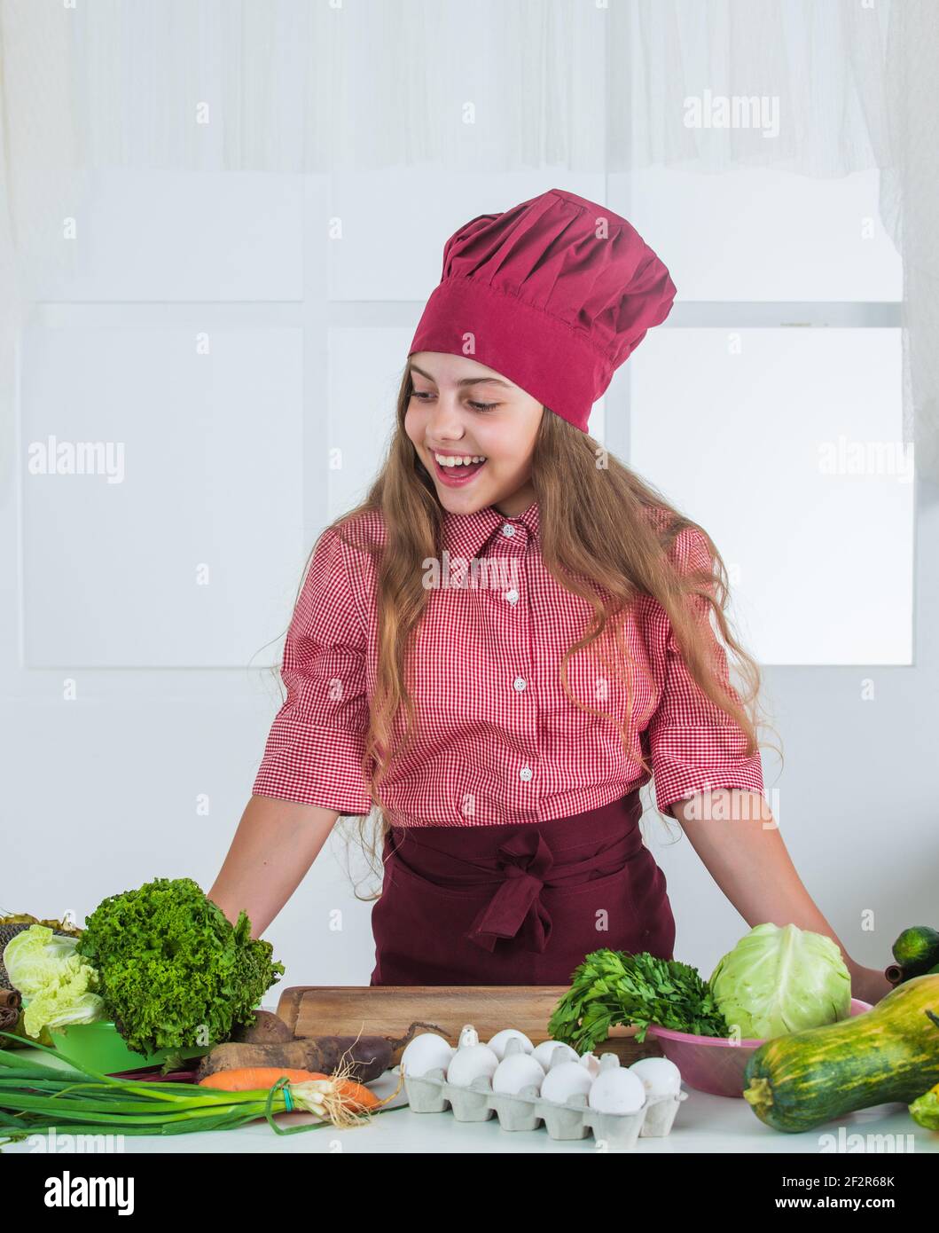 happy teen girl cooking vegetables. kid wearing professional chef ...