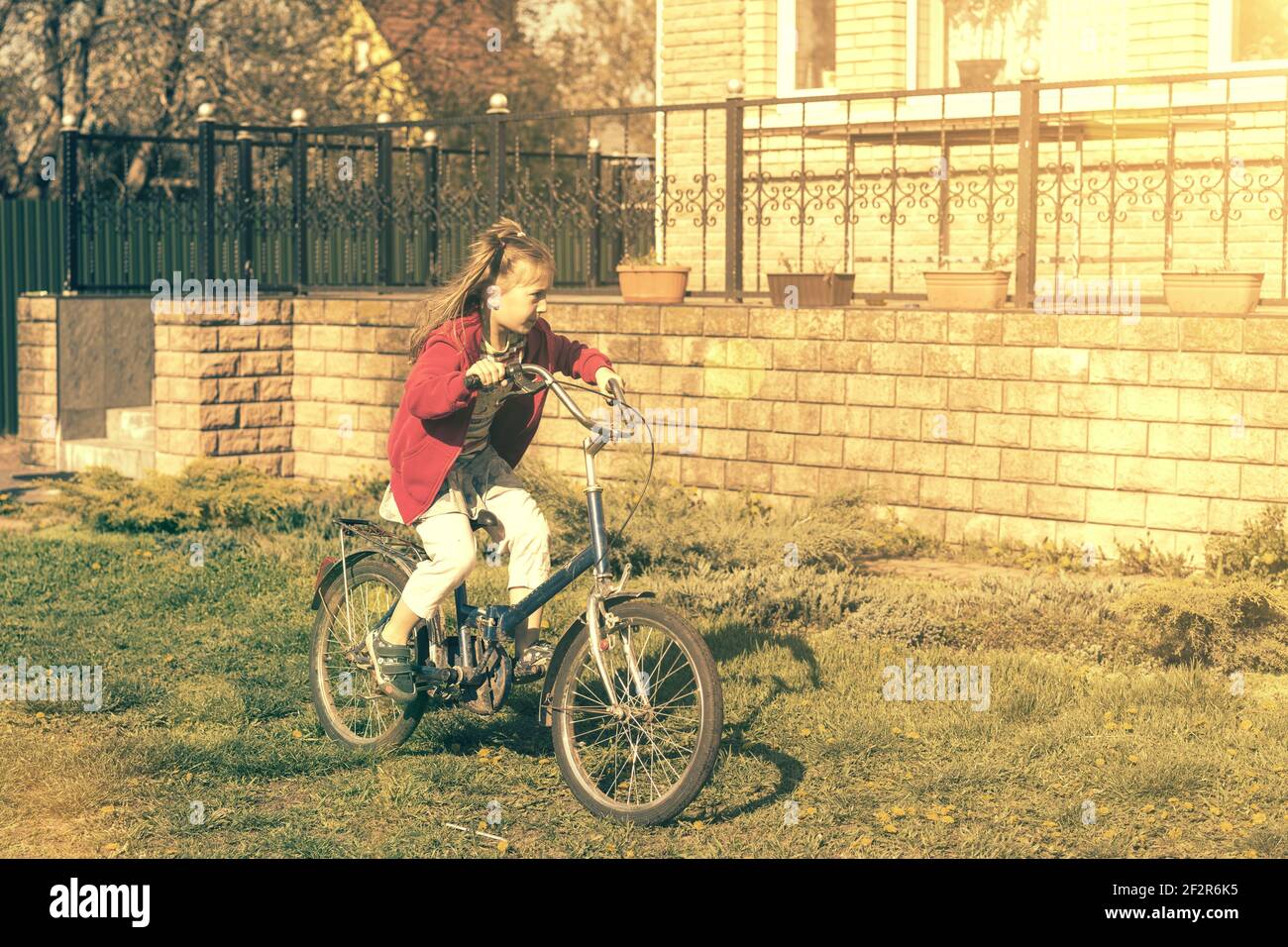 Girl riding a bike near the house. Girl on bicycle smiling while ride ...