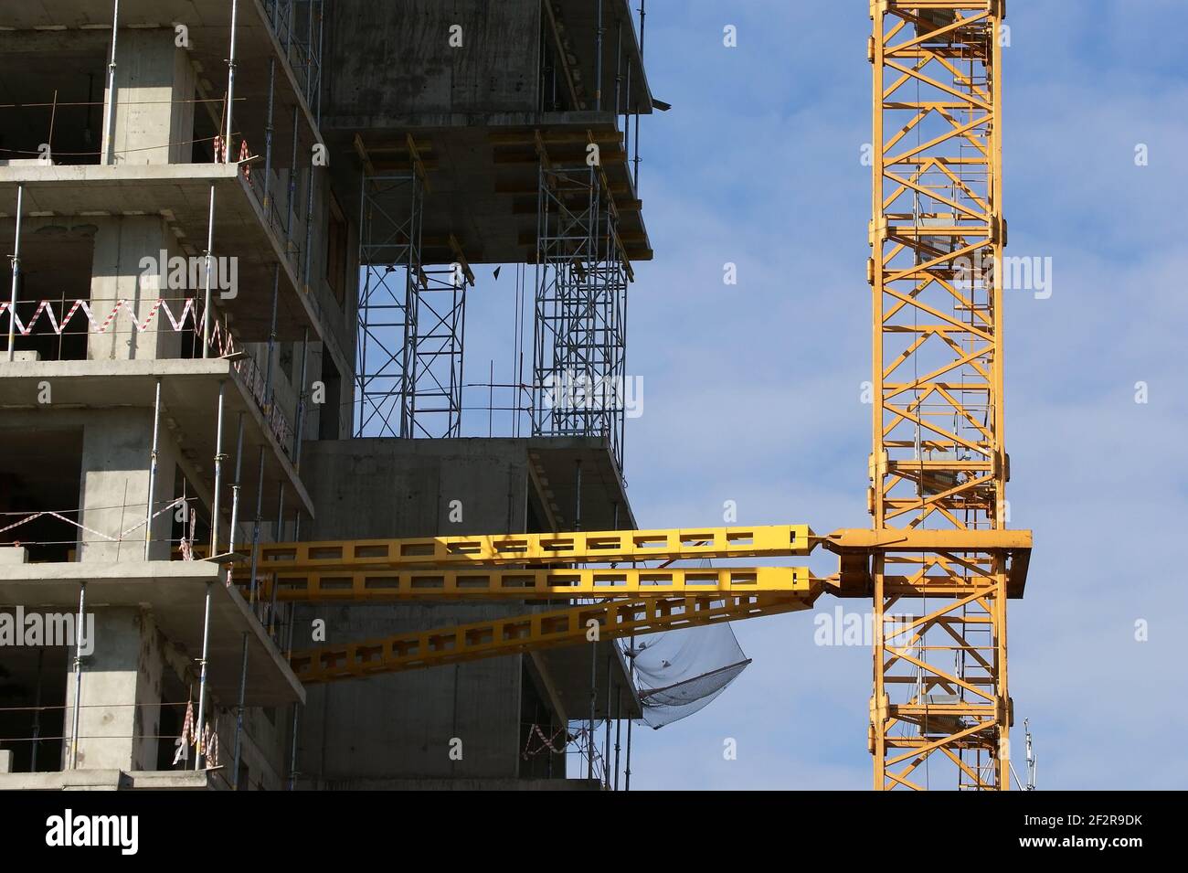 Building crane at the background of a multi-storey building under ...