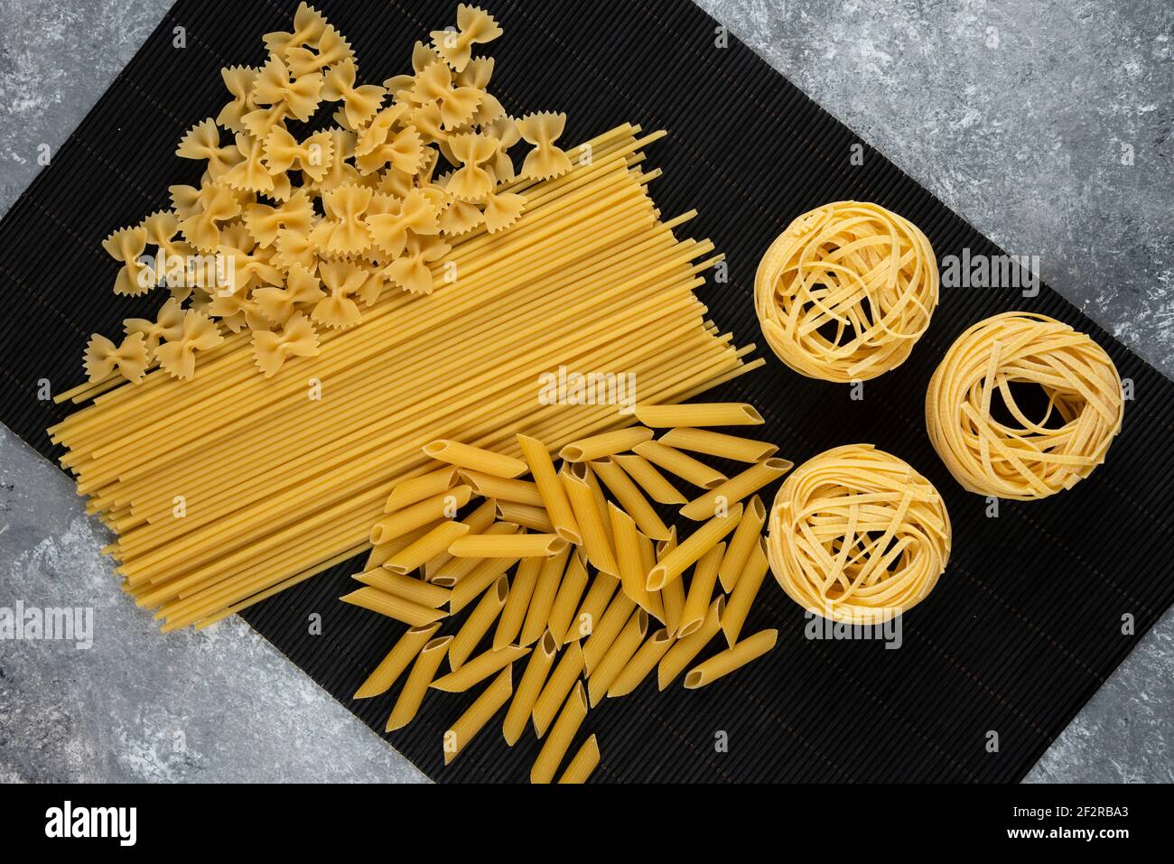 Various uncooked pasta on black bamboo sheet Stock Photo - Alamy