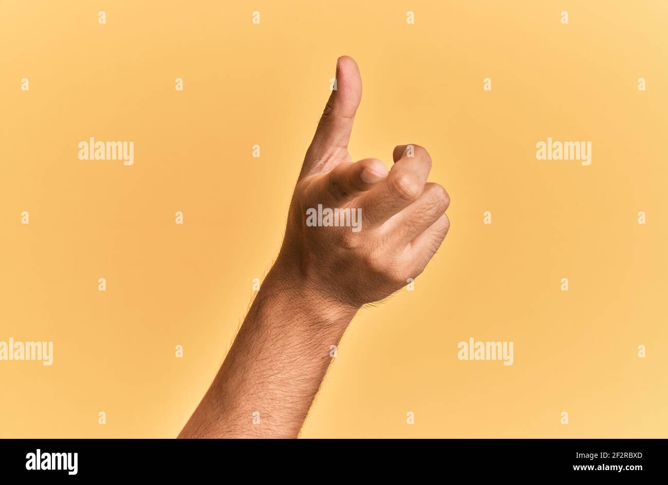 Arm and hand of caucasian man over yellow isolated background gesturing ...