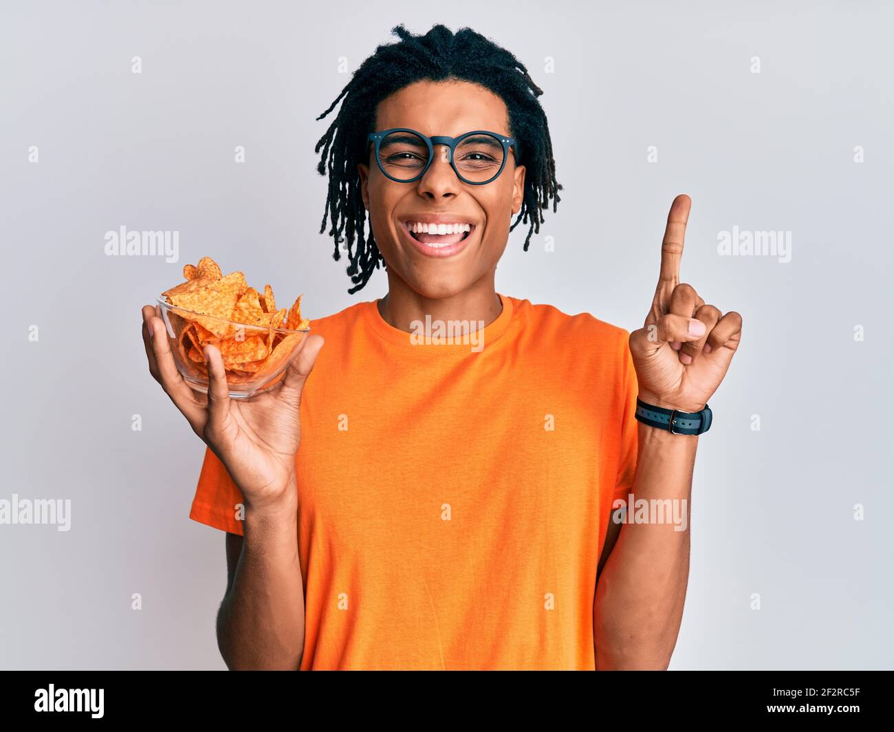 Young african american man holding nachos potato chips smiling with an ...