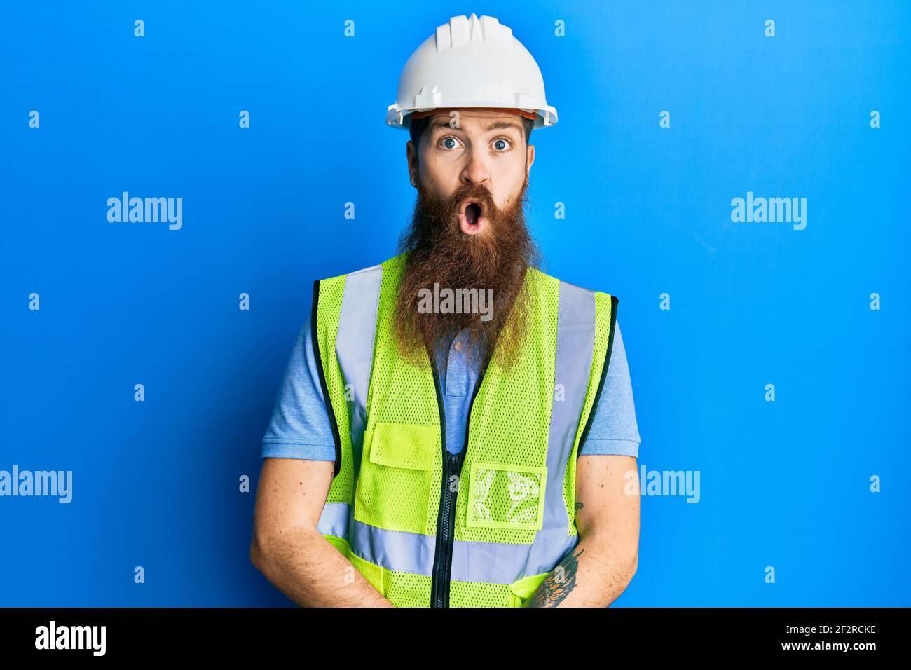 Redhead man with long beard wearing safety helmet and reflective jacket ...