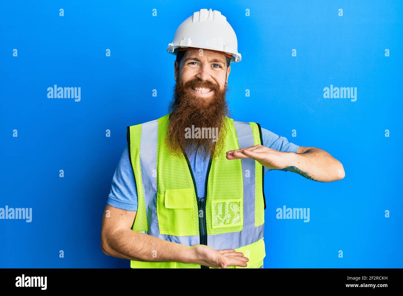 Redhead man with long beard wearing safety helmet and reflective jacket ...