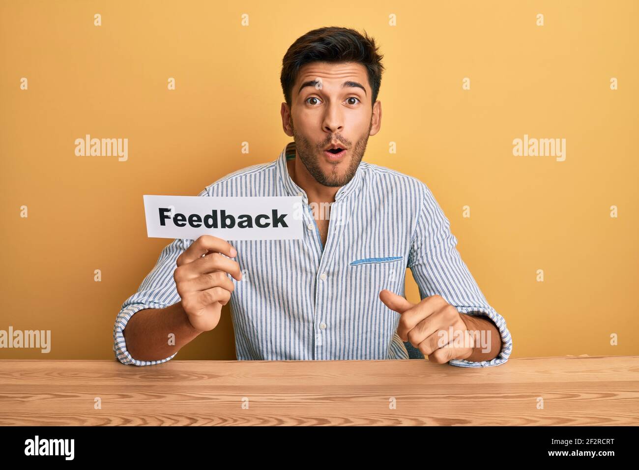 Young handsome man holding feedback paper for customer evaluation ...