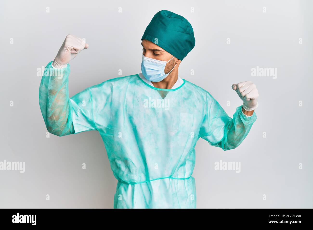 Young handsome man wearing surgeon uniform and medical mask showing ...