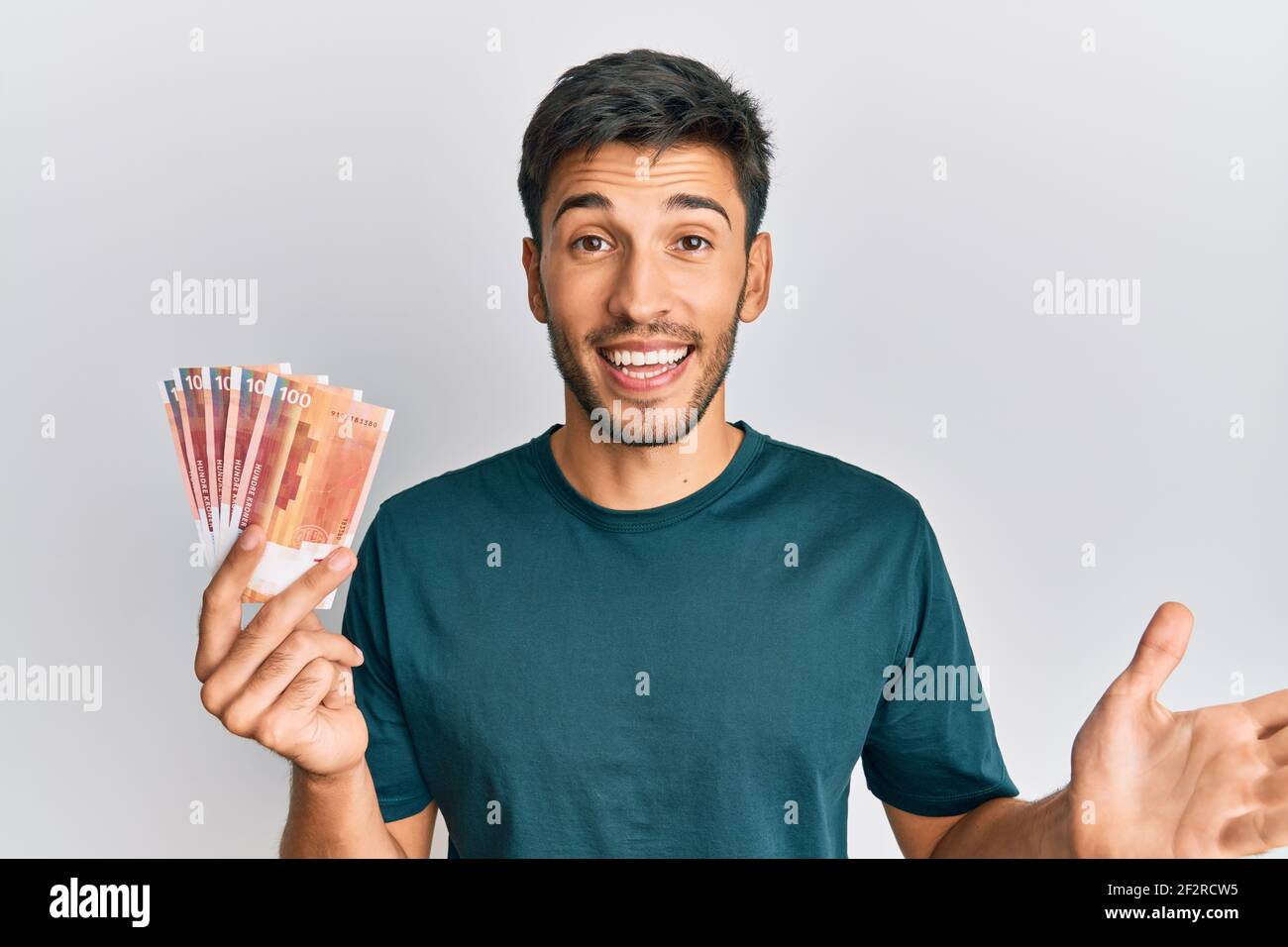 Young handsome man holding 100 norwegian krone banknotes celebrating ...