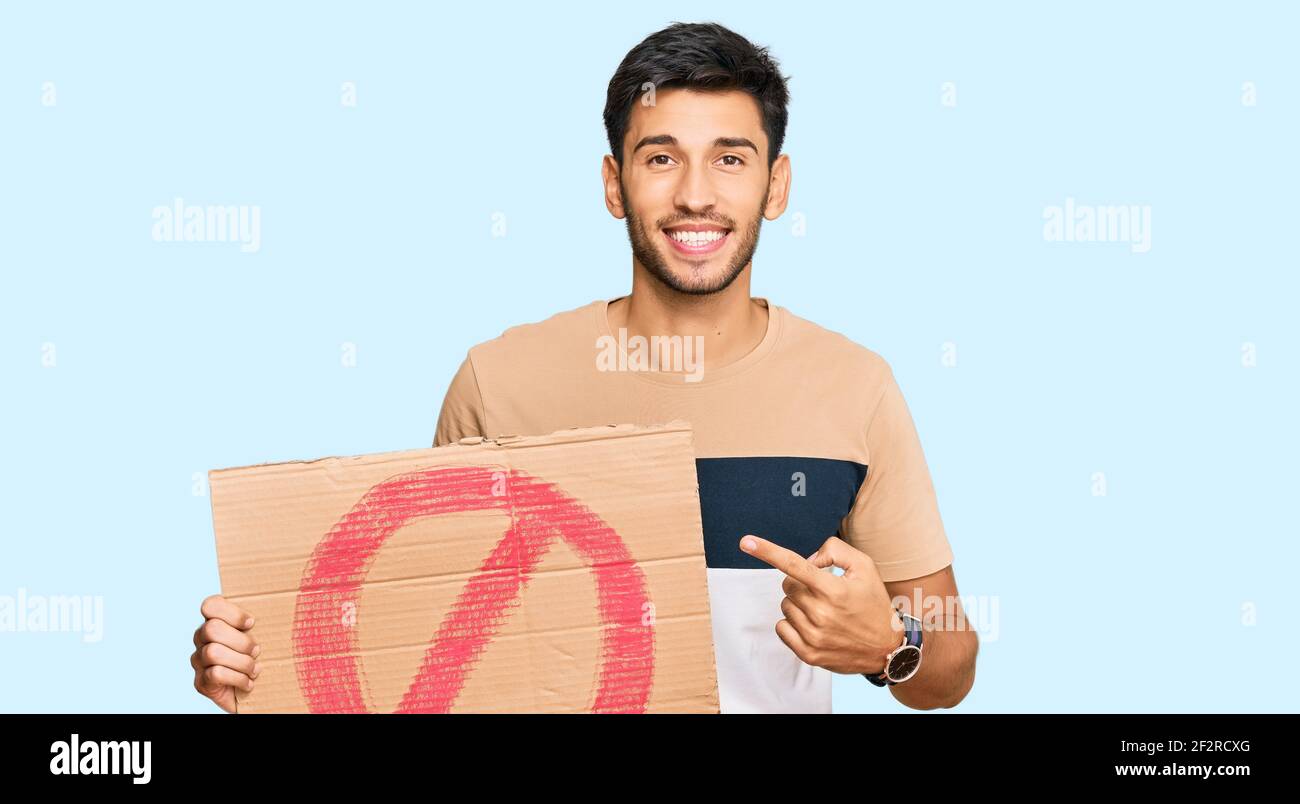 Young handsome man holding prohibited warning banner smiling happy ...