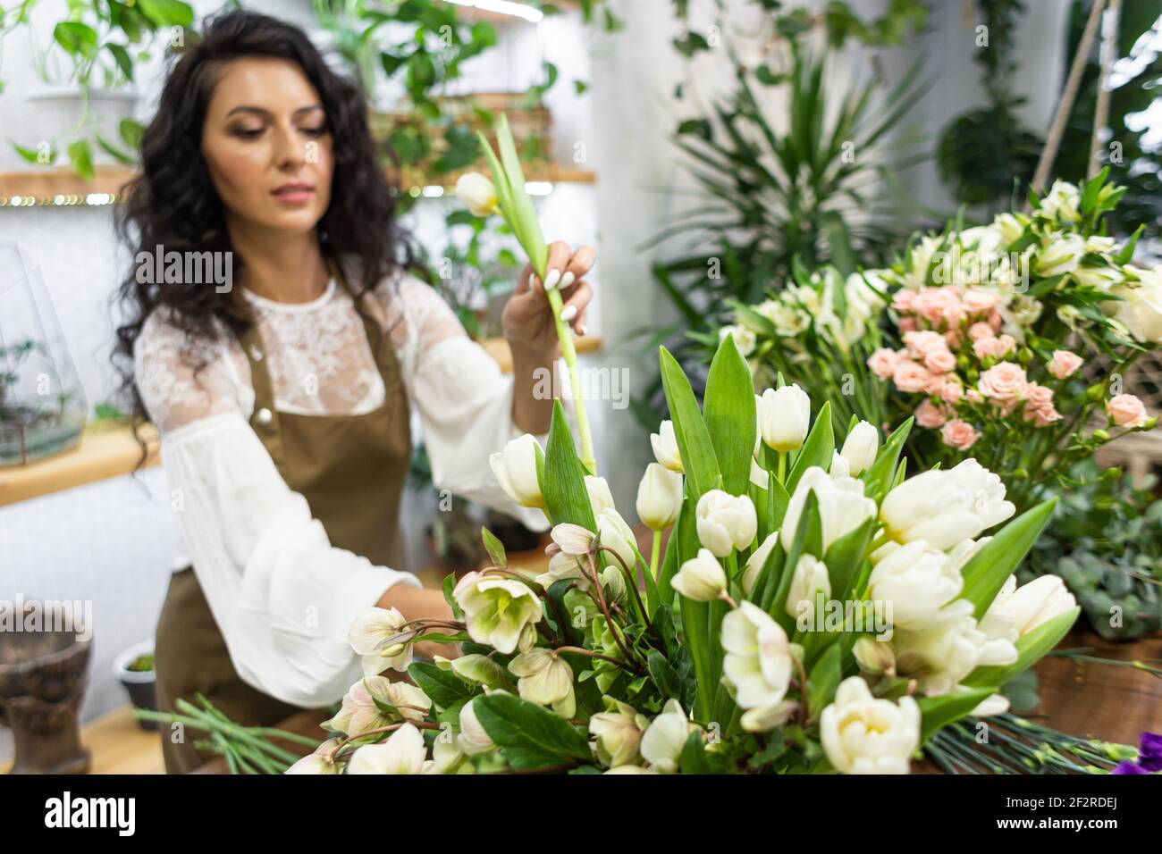 Attractive young woman florist is working in a flower shop Stock Photo ...