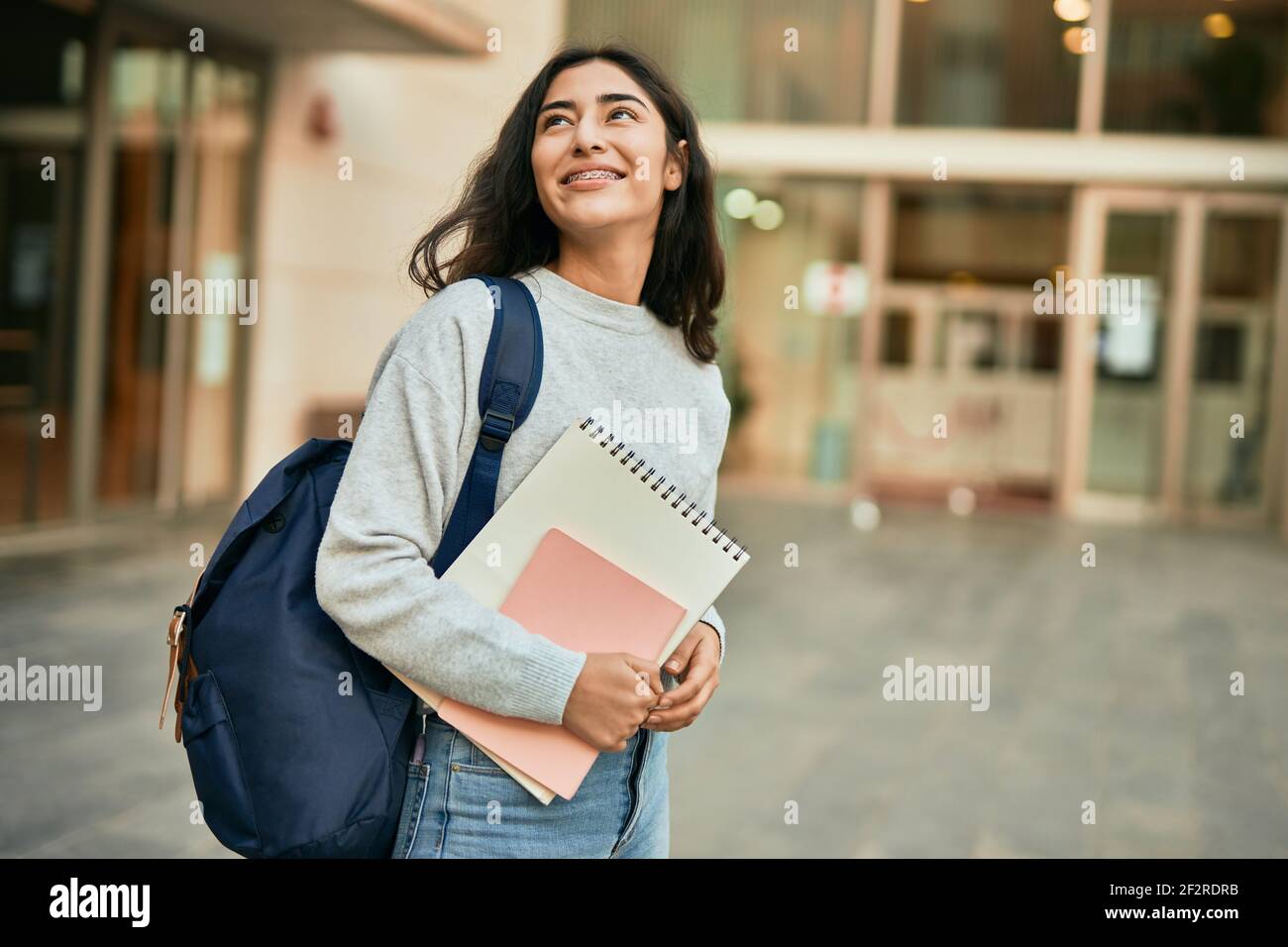 Young middle east student girl smiling happy holding book at the city ...