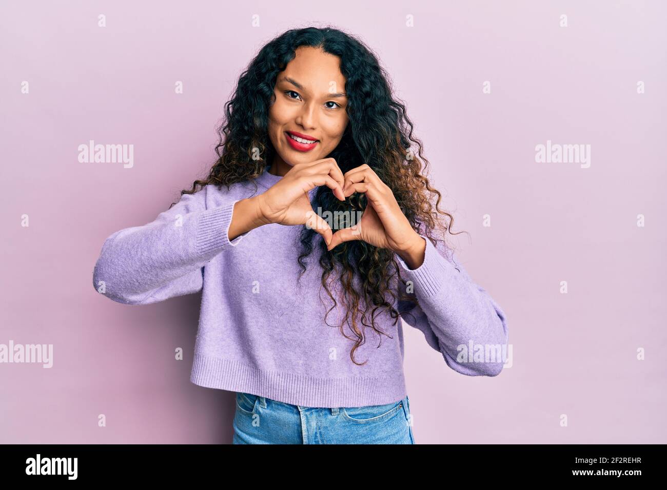 Young latin woman wearing casual clothes smiling in love doing heart ...