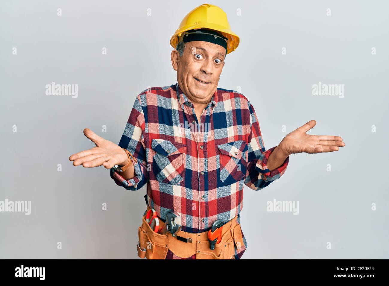 Senior hispanic man wearing handyman uniform clueless and confused ...