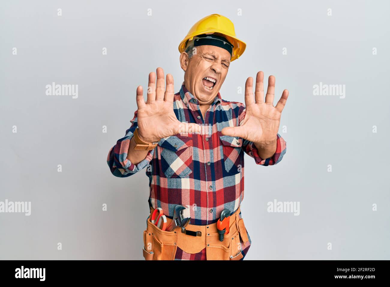 Senior hispanic man wearing handyman uniform afraid and terrified with ...
