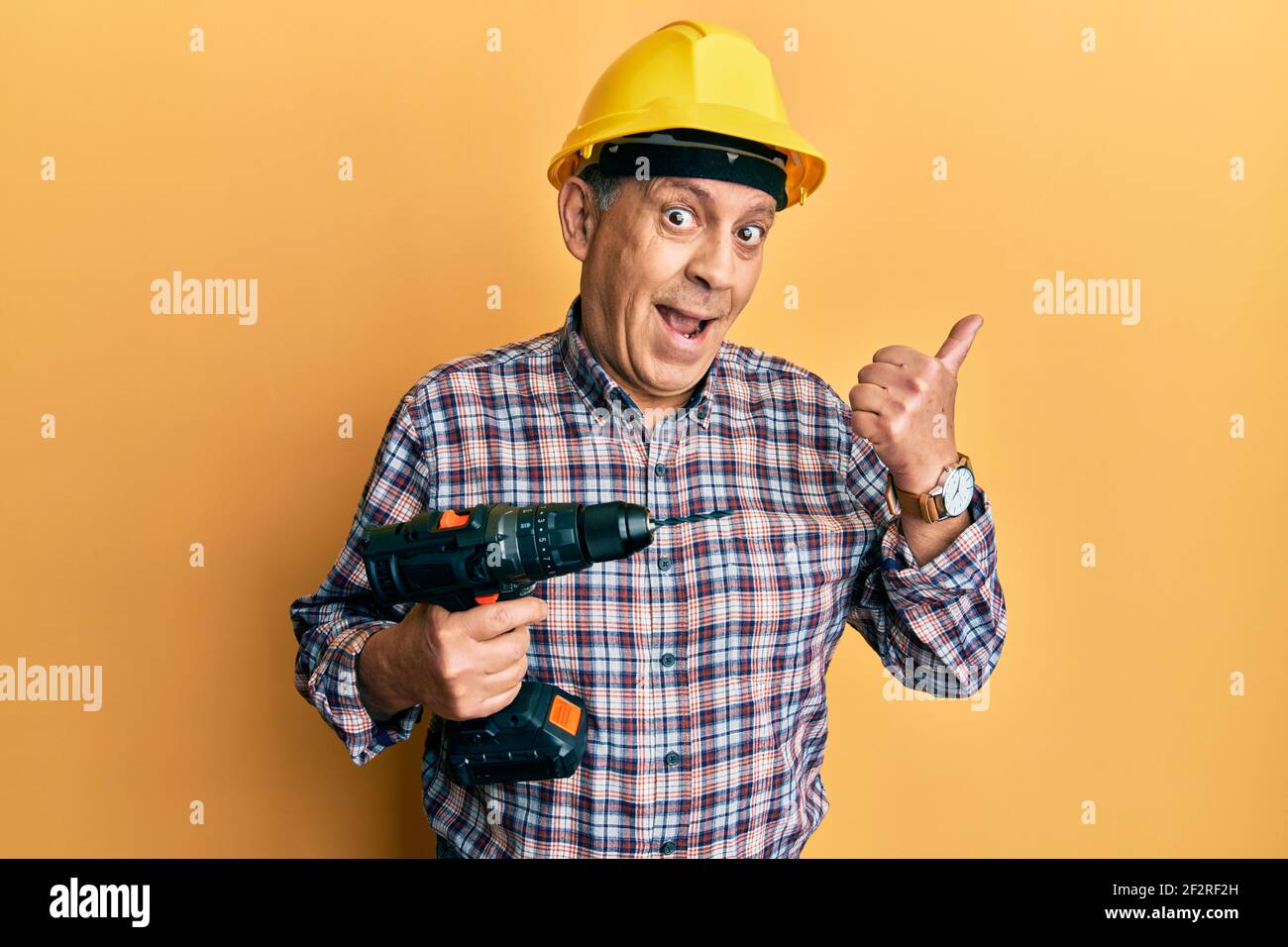 Handsome senior man with grey hair holding screwdriver wearing hardhat ...