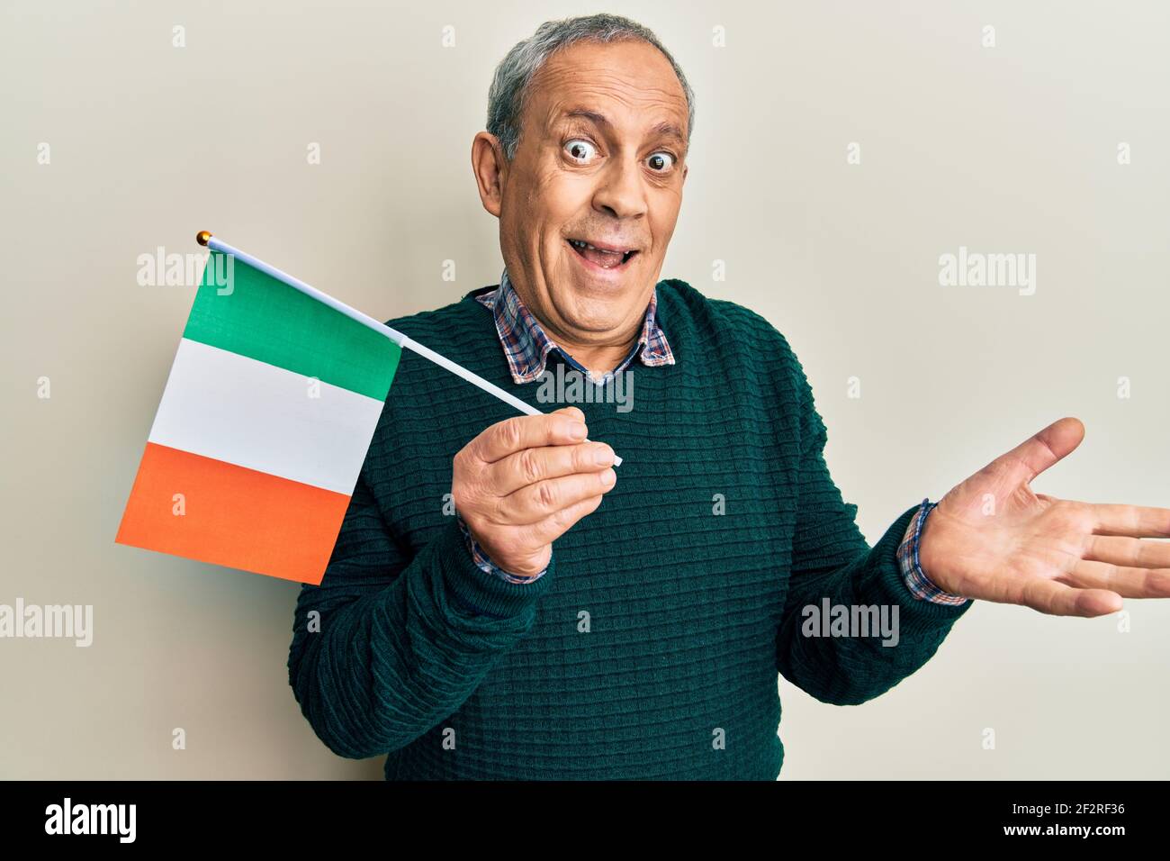 Handsome senior man with grey hair holding ireland flag celebrating ...