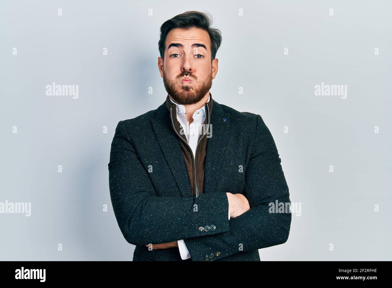 Handsome caucasian man with beard with arms crossed gesture puffing ...