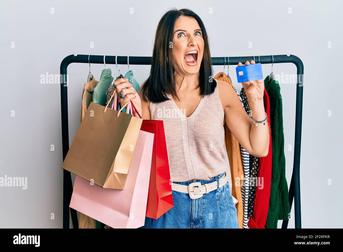 Middle age brunette personal shopper woman holding shopping bags and ...