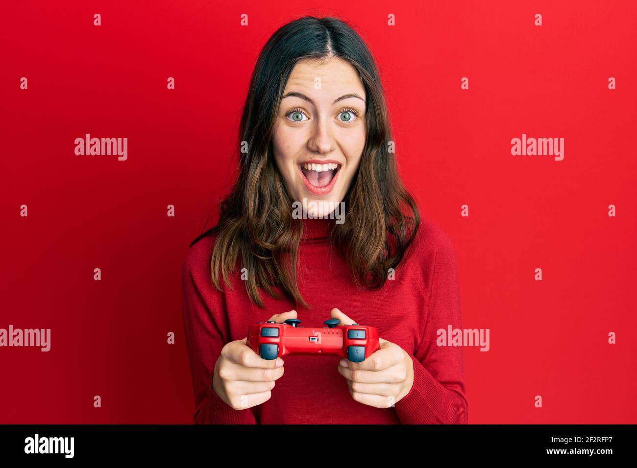 Young brunette woman playing video game holding controller celebrating ...