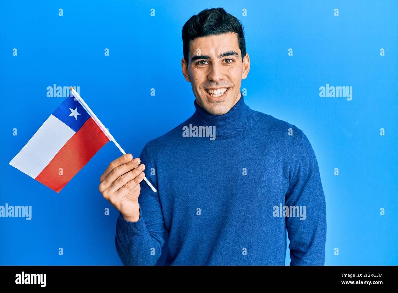 Handsome hispanic business man holding chile flag looking positive and ...
