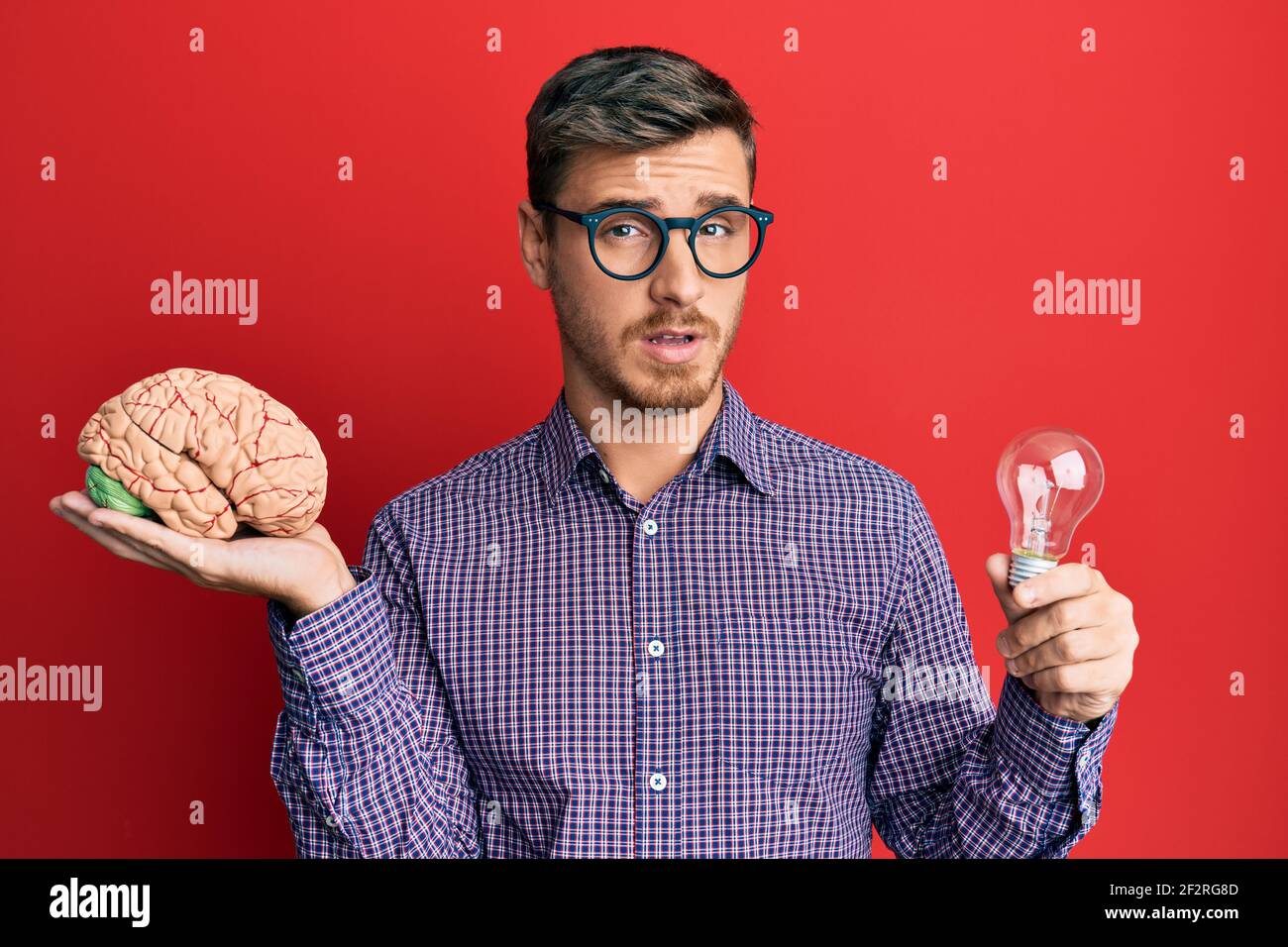 Handsome caucasian man holding brain and lightbulb for inspiration and ...