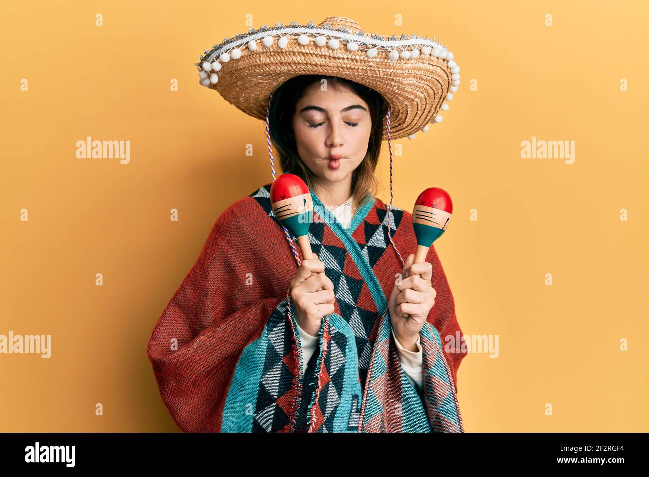 Young caucasian woman holding mexican hat using maracas making fish ...