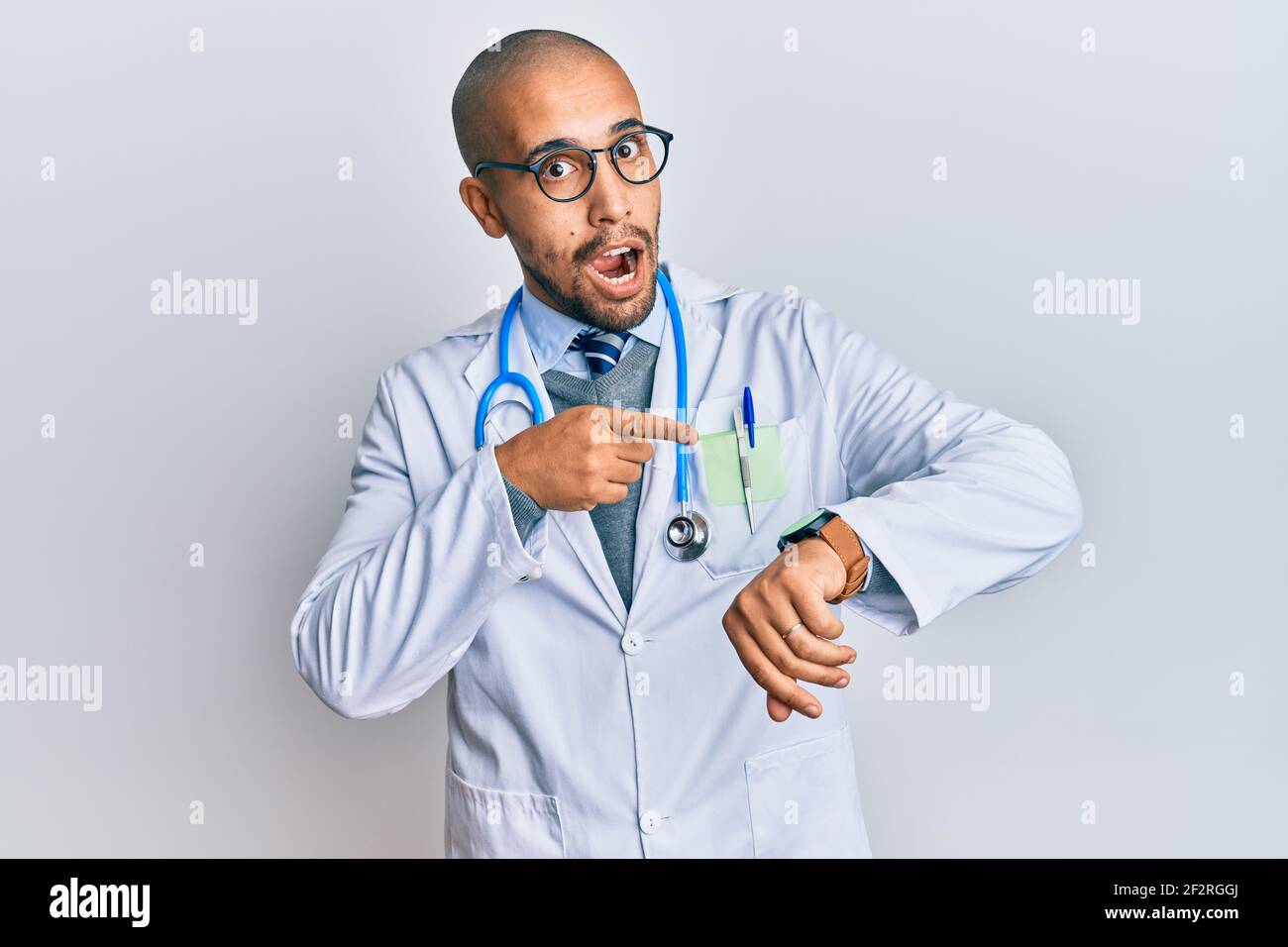 Hispanic adult man wearing doctor uniform and stethoscope in hurry ...