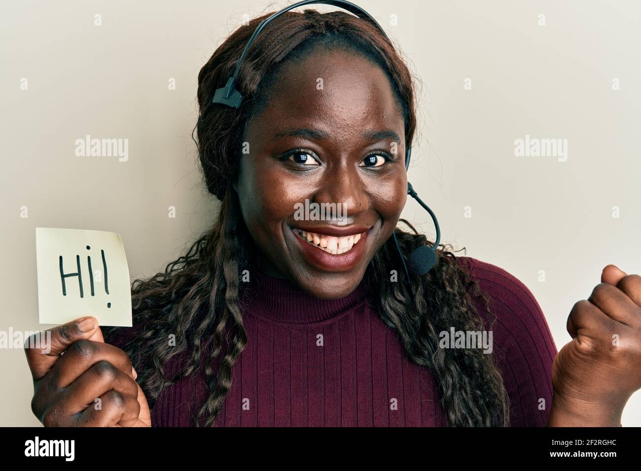 African young woman wearing operator headset showing hi greeting ...