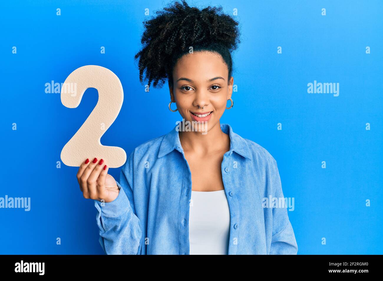 Young african american girl holding number two looking positive and ...
