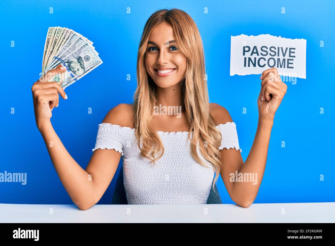 Beautiful blonde young woman holding dollars and passive income text ...