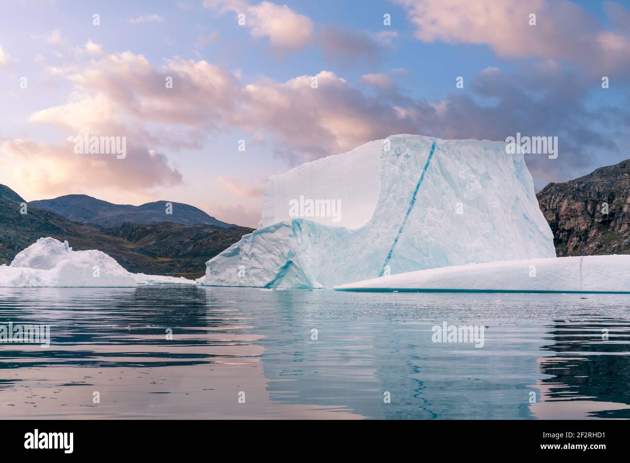 Big blue iceberg reflecting in water floats in the sea by Broughton ...