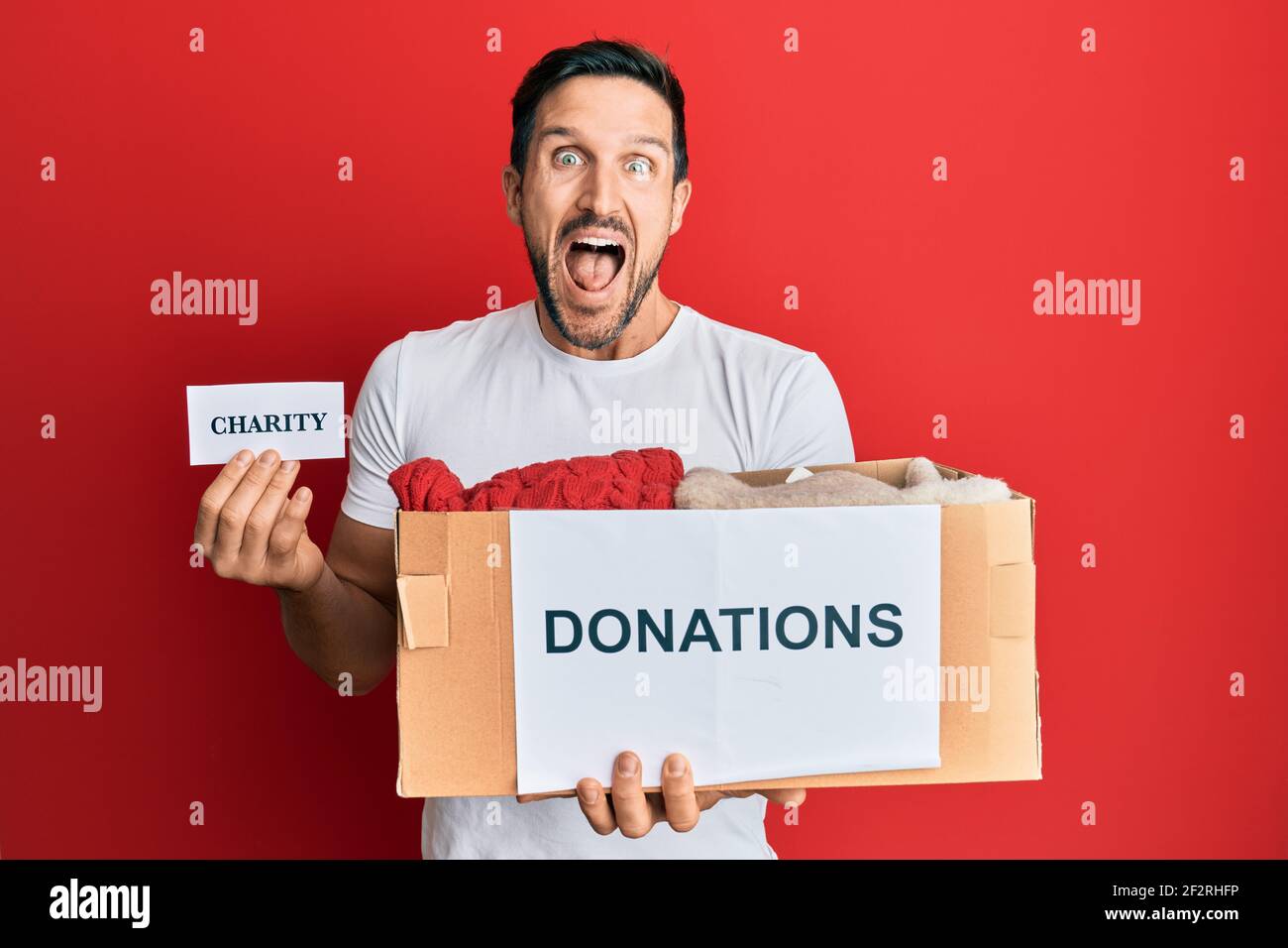 Young handsome man volunteer holding donations box with clothes ...