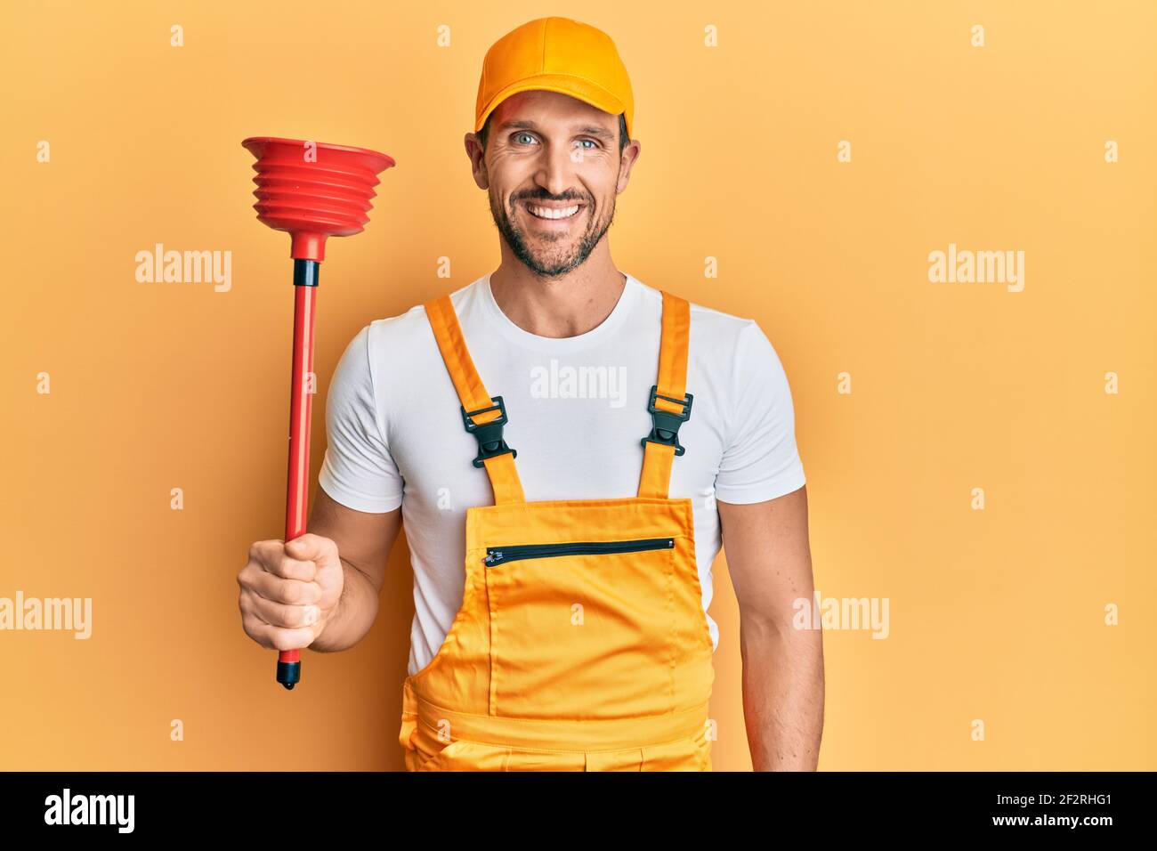 Young handsome man wearing plumber uniform holding toilet plunger ...