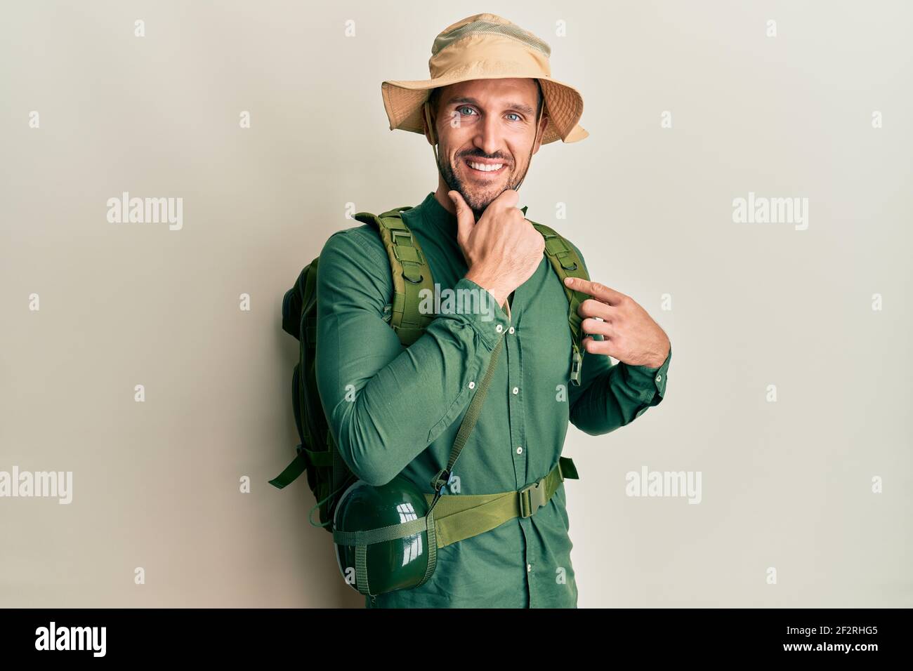 Handsome man with beard wearing explorer hat and backpack looking ...