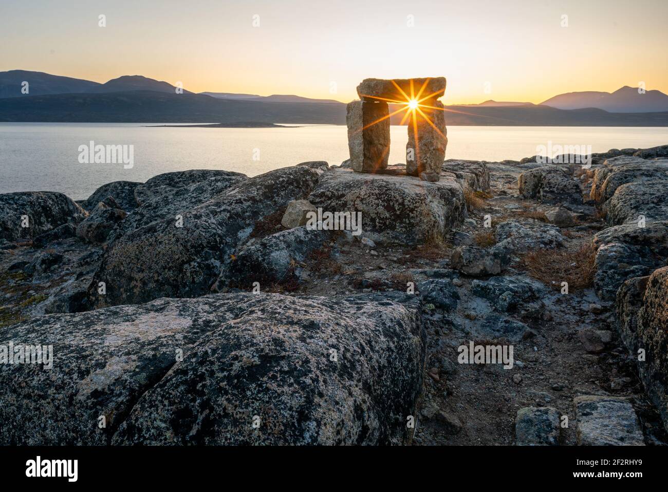 Sunset through Inuksuk in rough arctic landscape. Sunstar on the ...