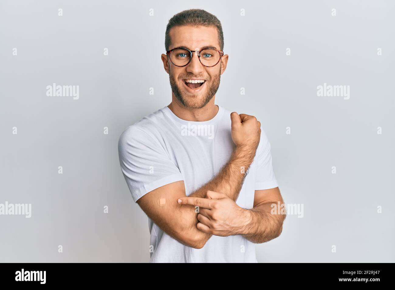 Young caucasian man wearing band aid for vaccine injection smiling and ...