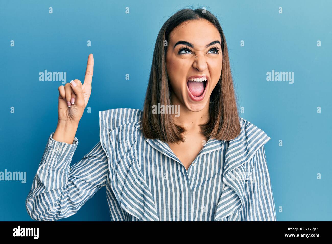 Young brunette student girl pointing up with finger angry and mad ...