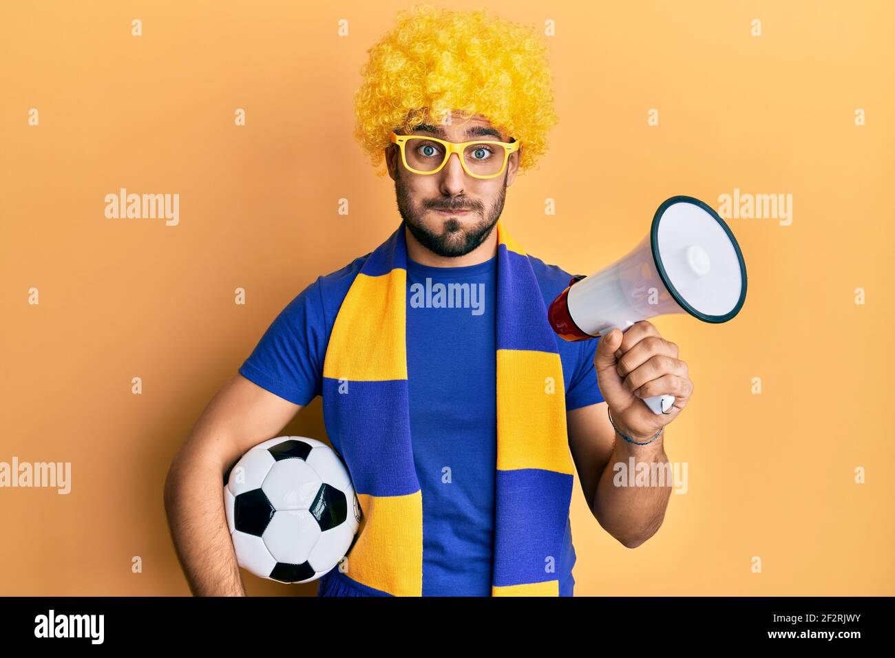 Young hispanic man football supporter holding soccer ball using ...