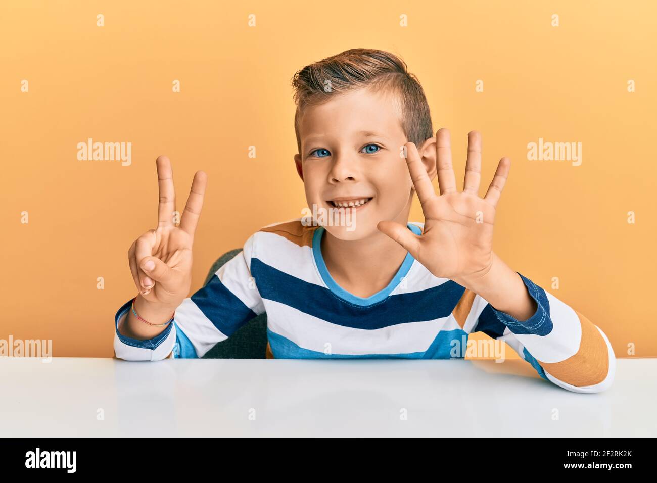 Adorable caucasian kid wearing casual clothes sitting on the table ...