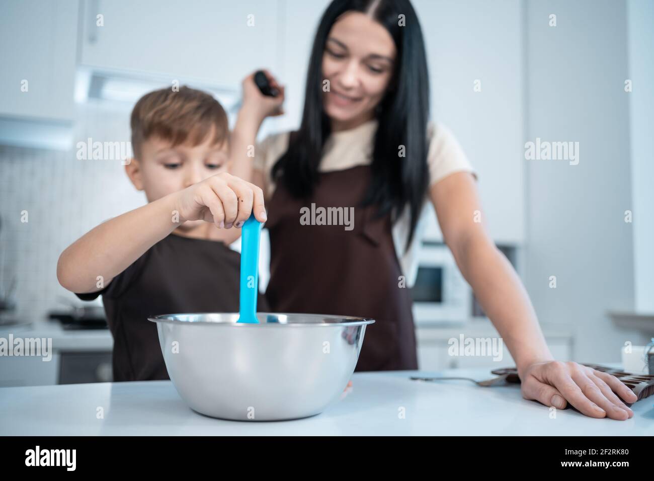 mother and kid make home sweets and measure melted chocolate at modern ...