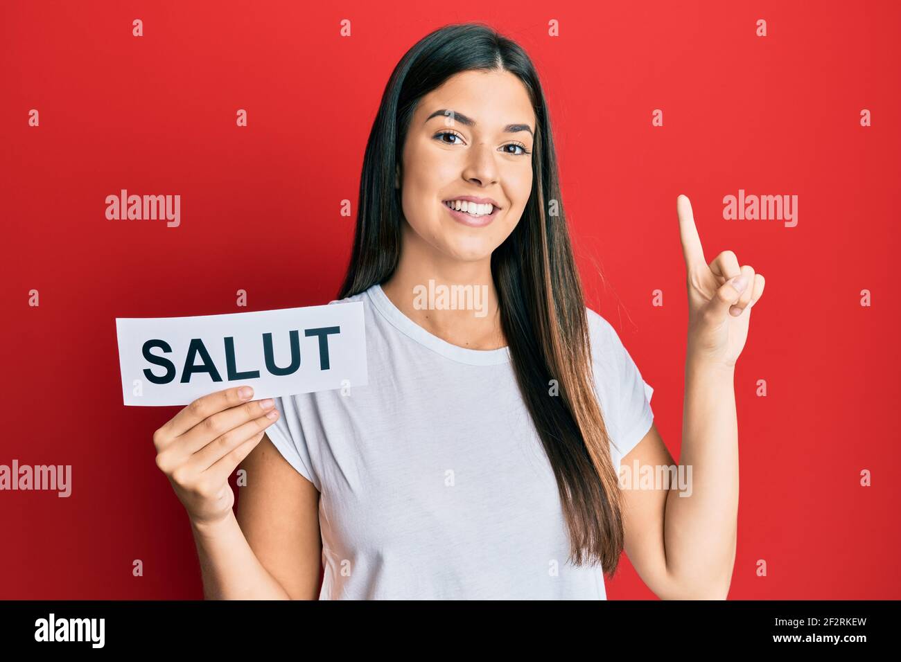 Young brunette woman holding salut french greeting smiling with an idea ...
