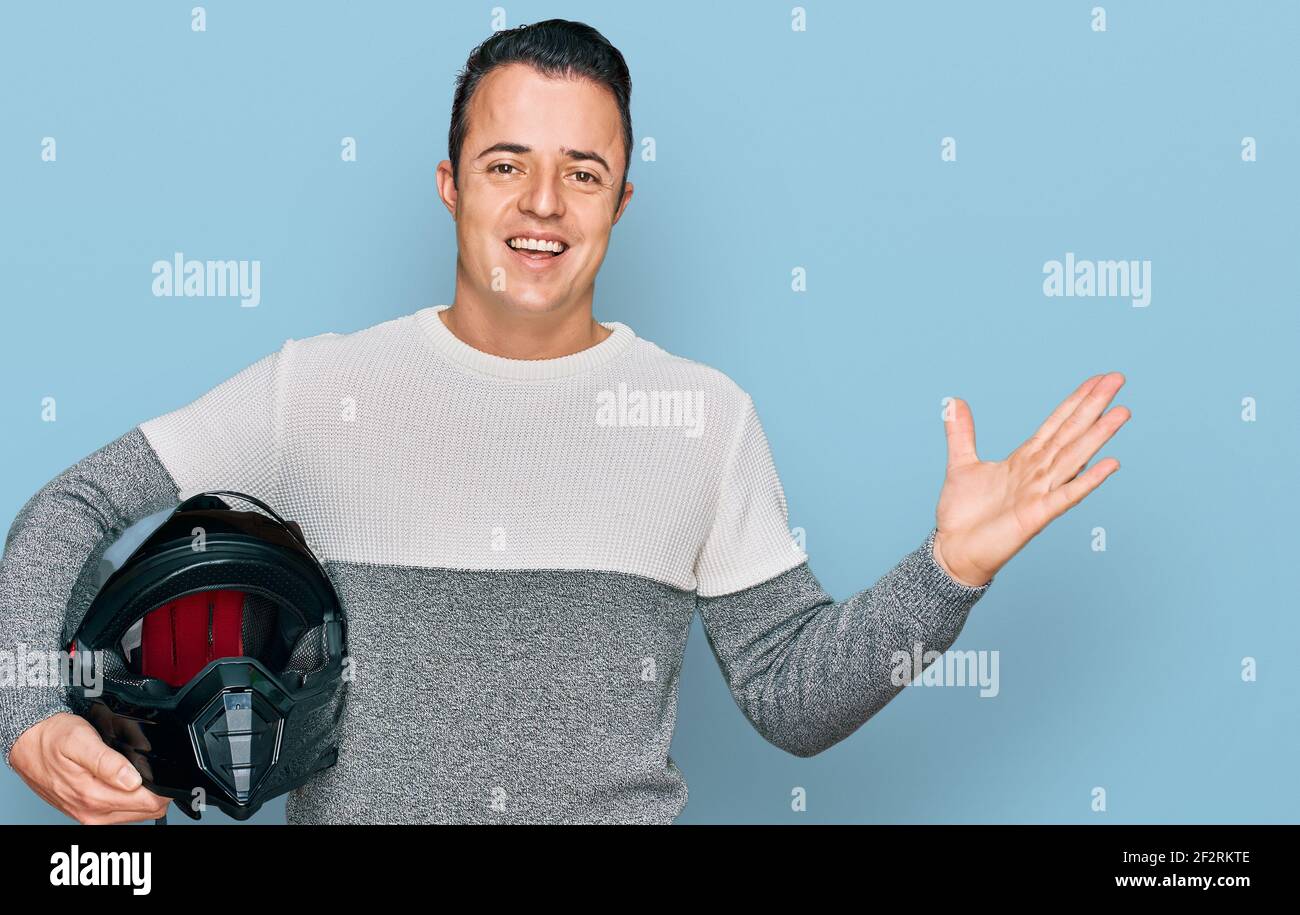 Handsome young man holding motorcycle helmet celebrating victory with ...