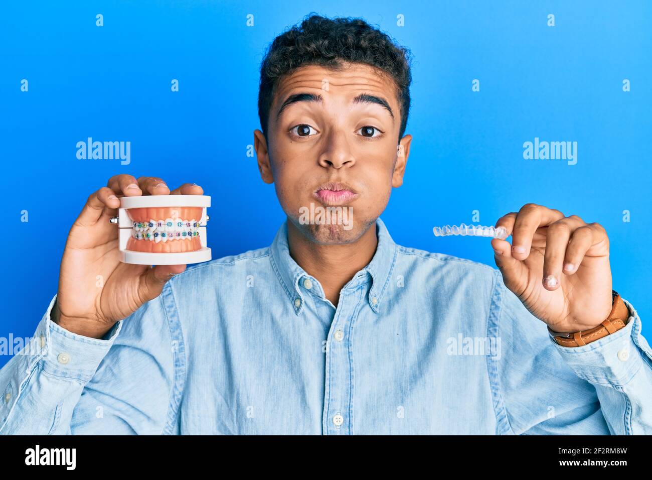 Young handsome african american man holding invisible aligner ...