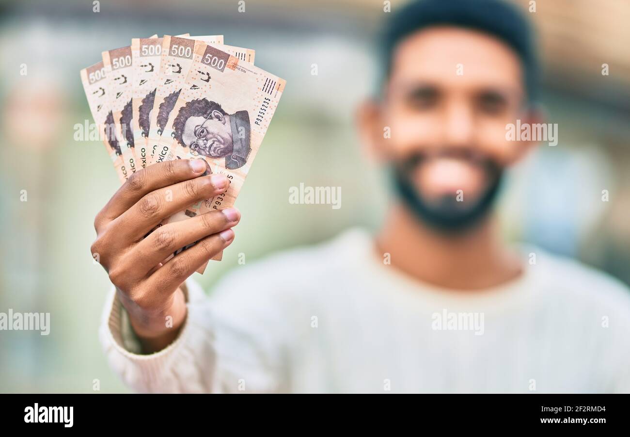 Young african american man smiling happy holding mexican 500 pesos ...