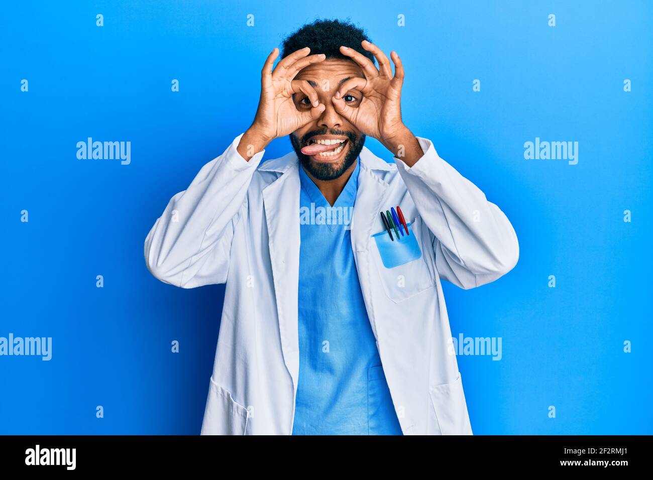 Handsome hispanic man with beard wearing doctor uniform doing ok ...